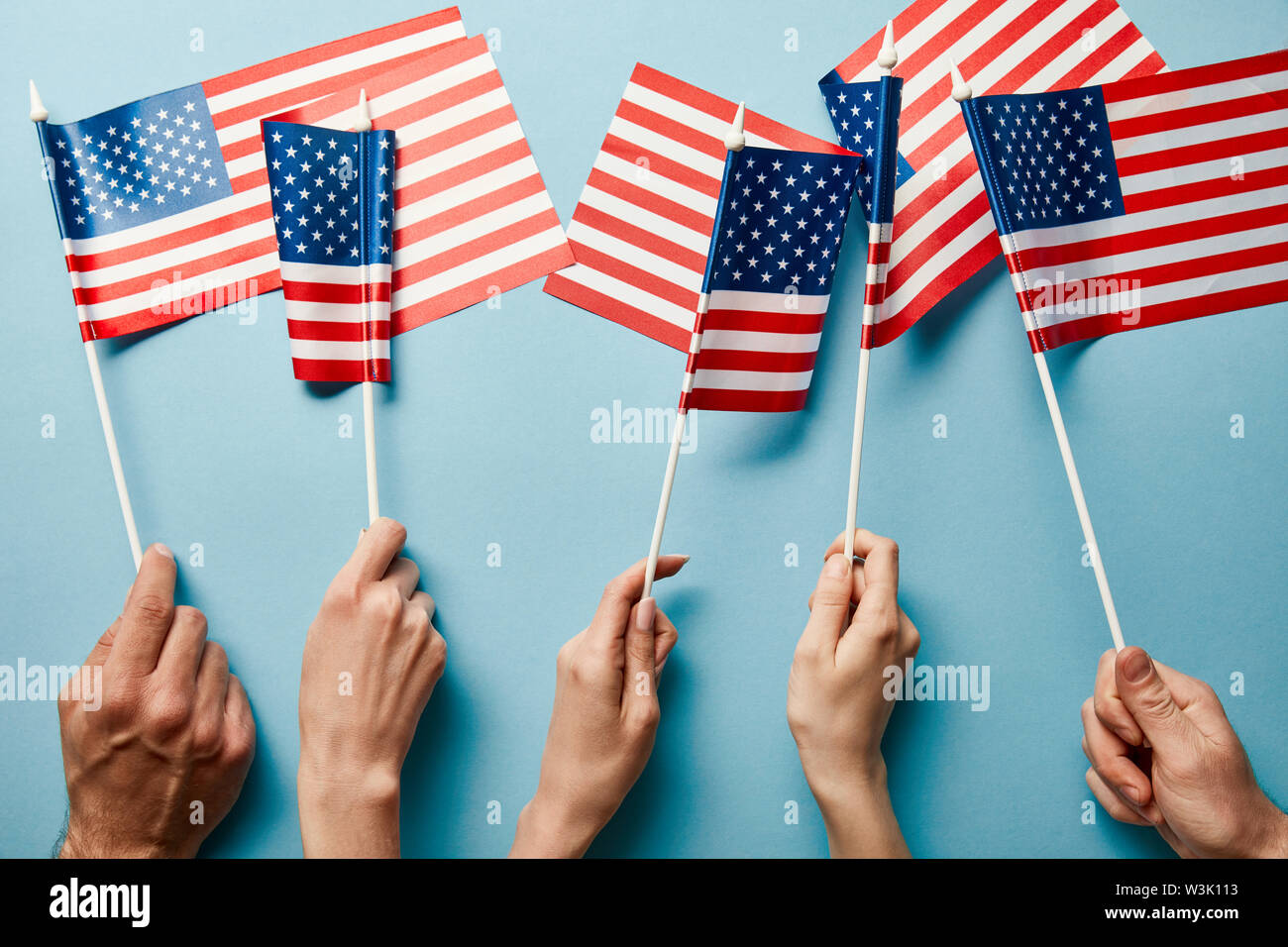 partial view of people holding american flags on blue background Stock ...