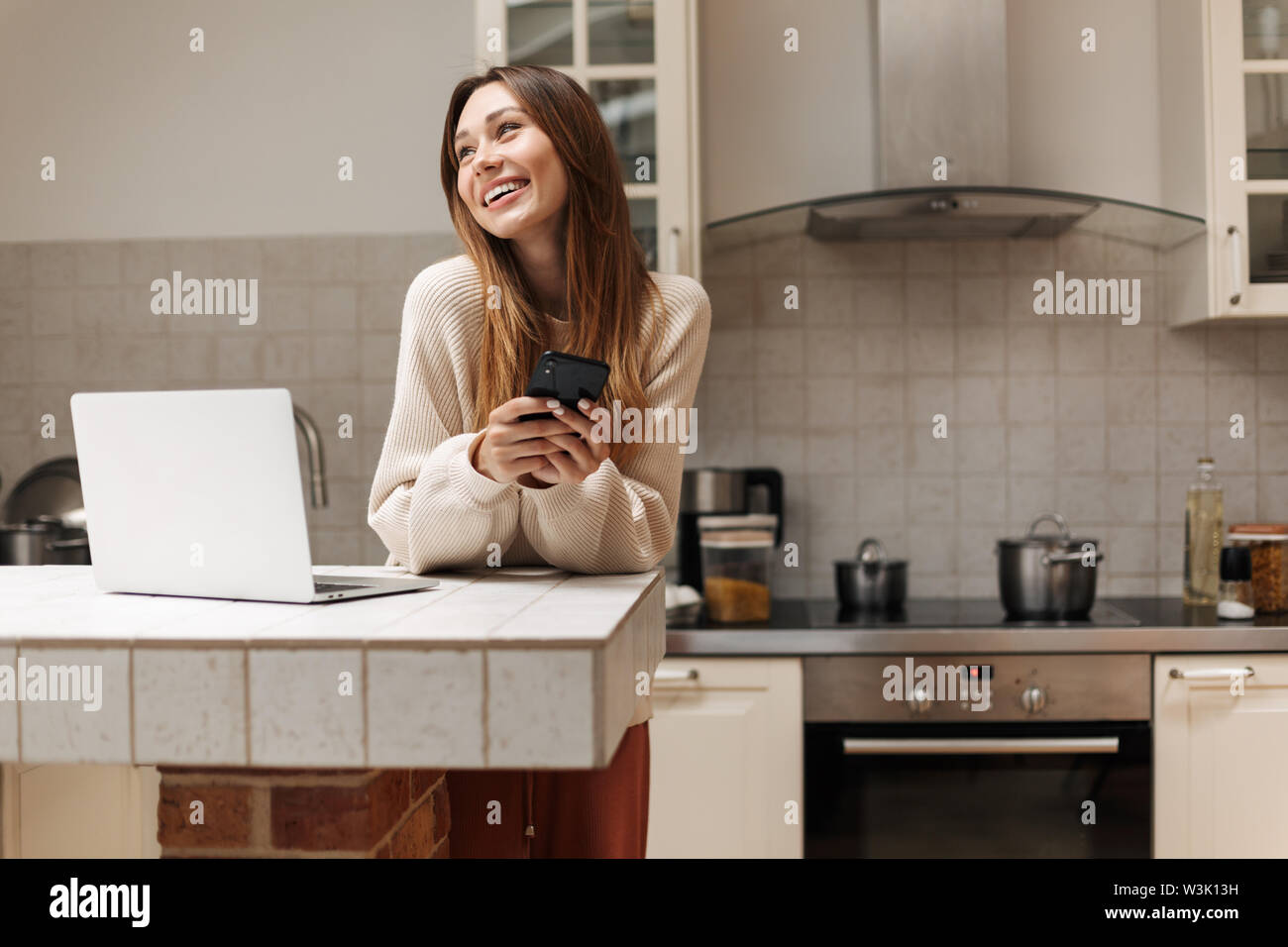 Beautiful young woman using mobile phone and laptop computer while ...