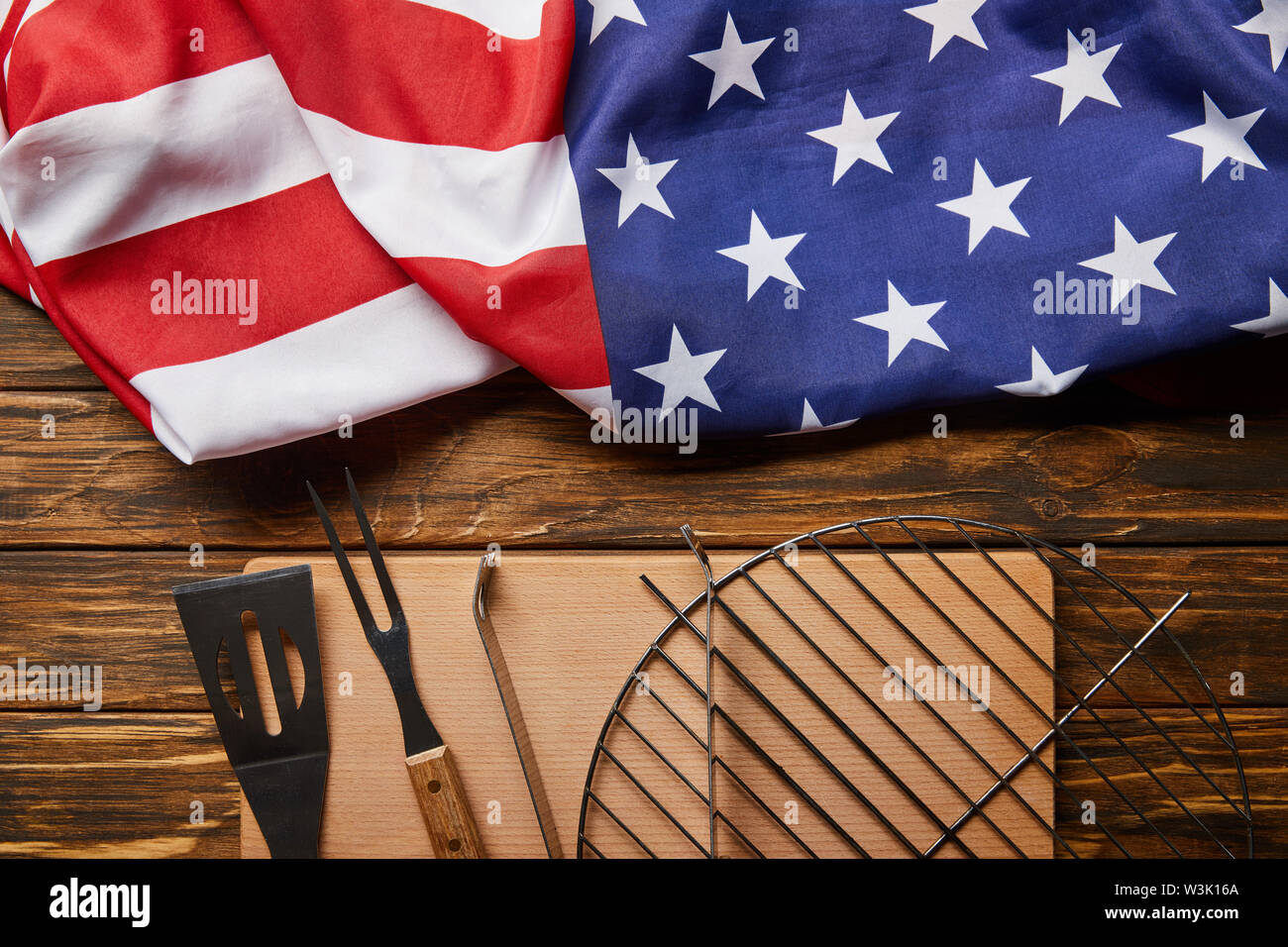 top view of crumpled american flag and bbq equipment on wooden rustic ...