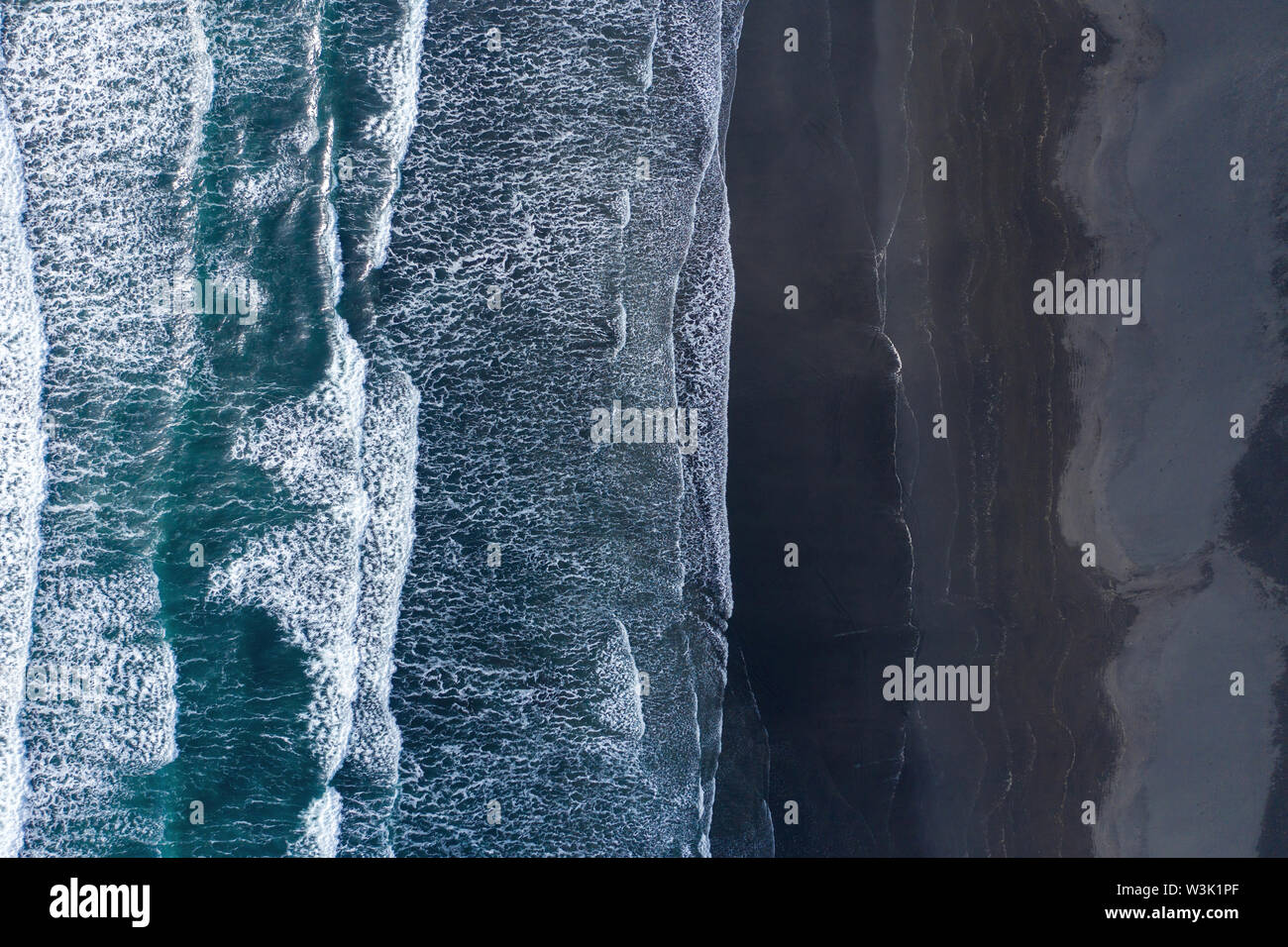 Aerial drone view of ocean waves washing black basaltic sand beach ...