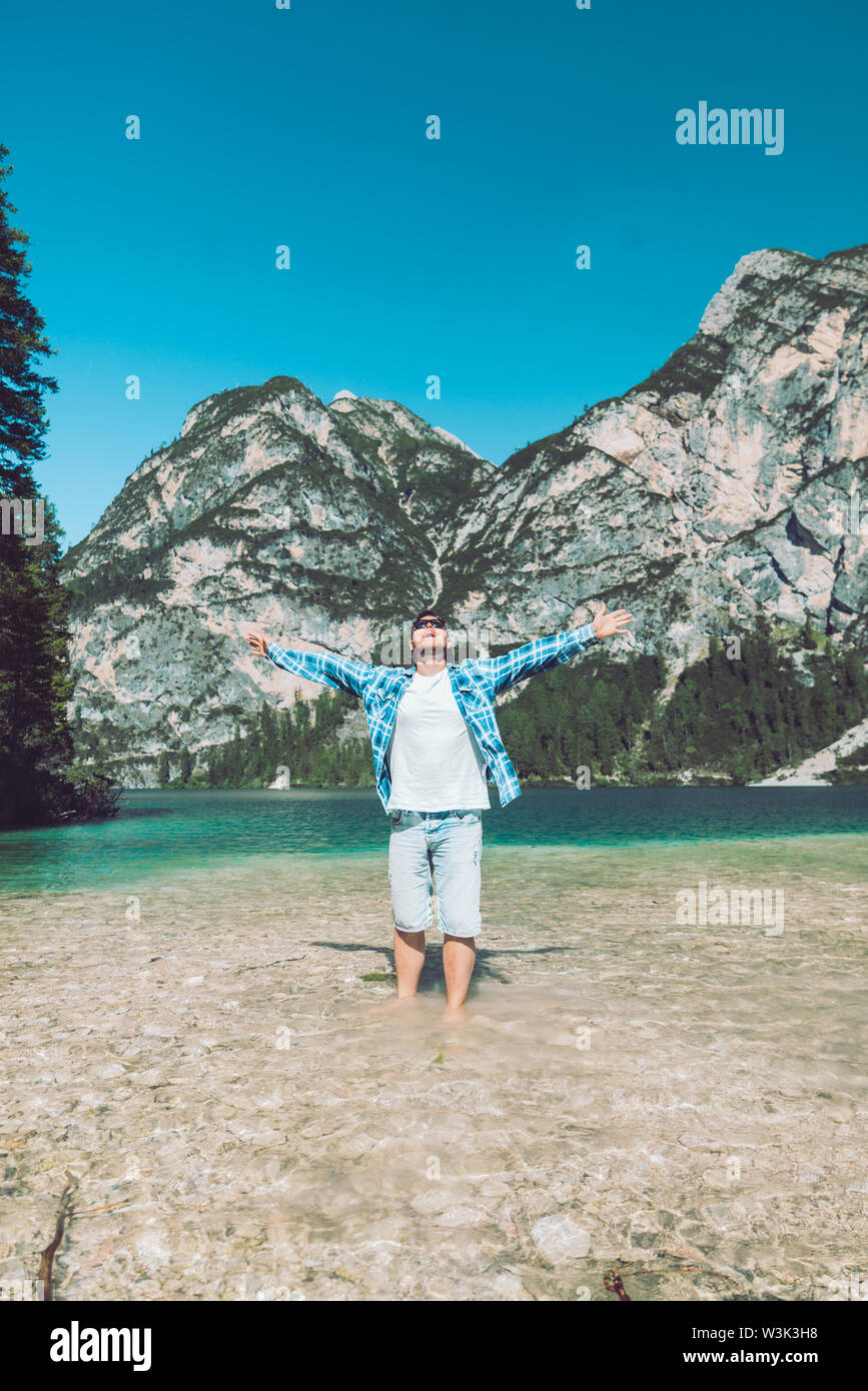 man rise up hands standing in lake mountains on background hiking ...