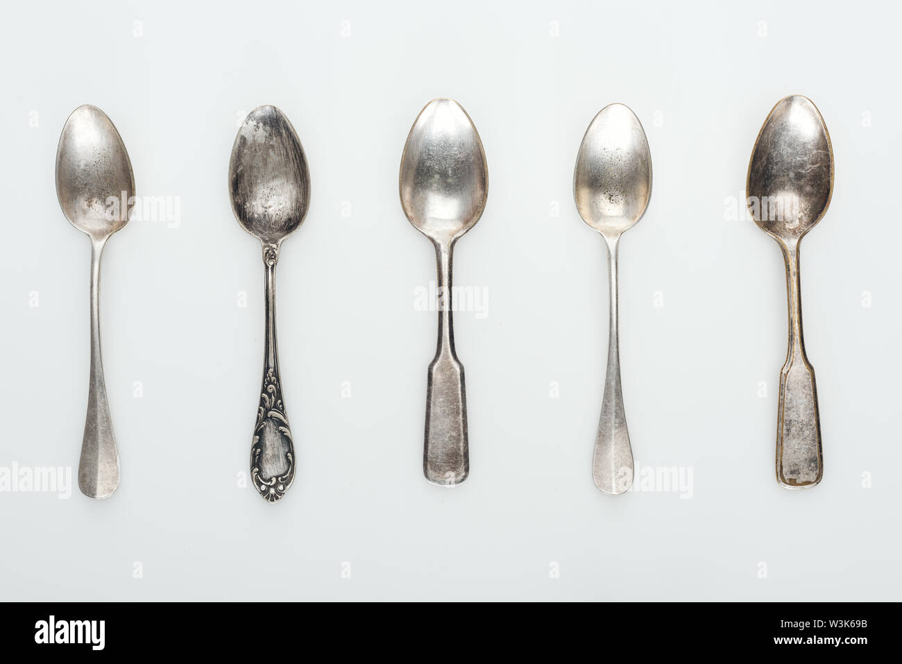 top view of shiny aged silver empty spoons in row on white background ...