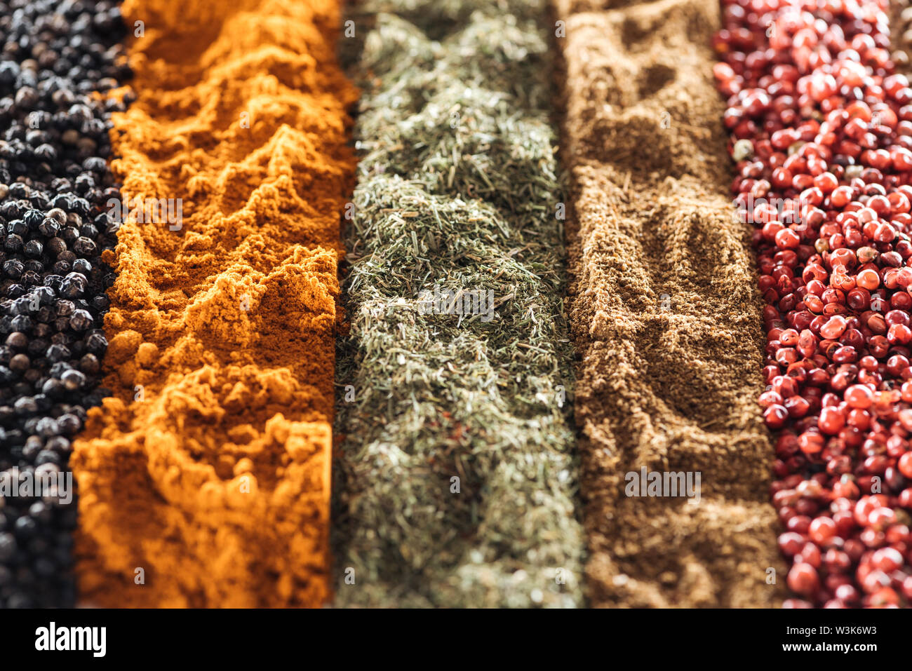 close up view of various aromatic traditional indian spices in rows ...
