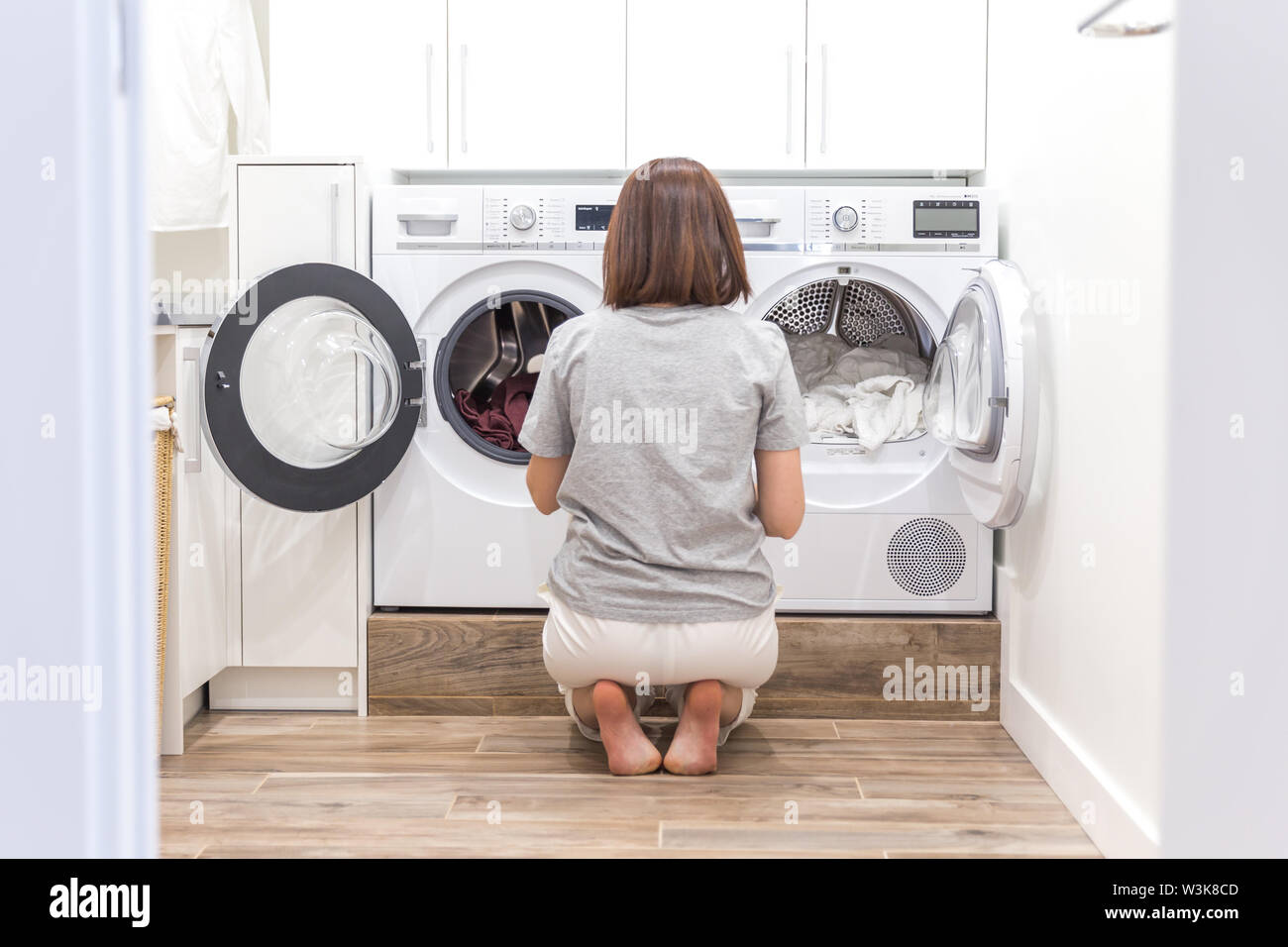 Woman Loading Dirty Clothes In Washing Machine For Washing In Utility ...