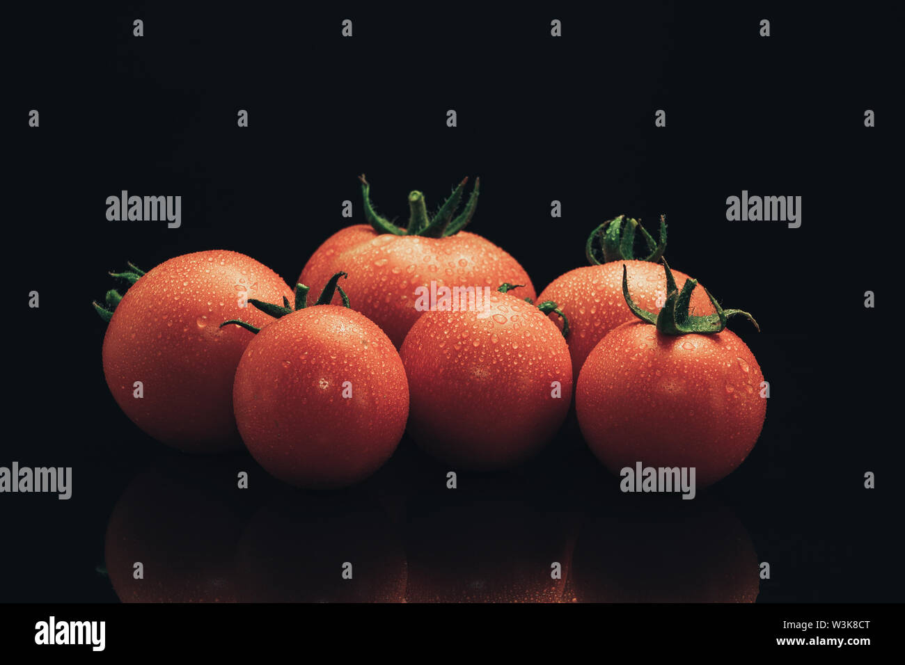 Fresh six tomato on a black glass table and dark background Stock Photo ...