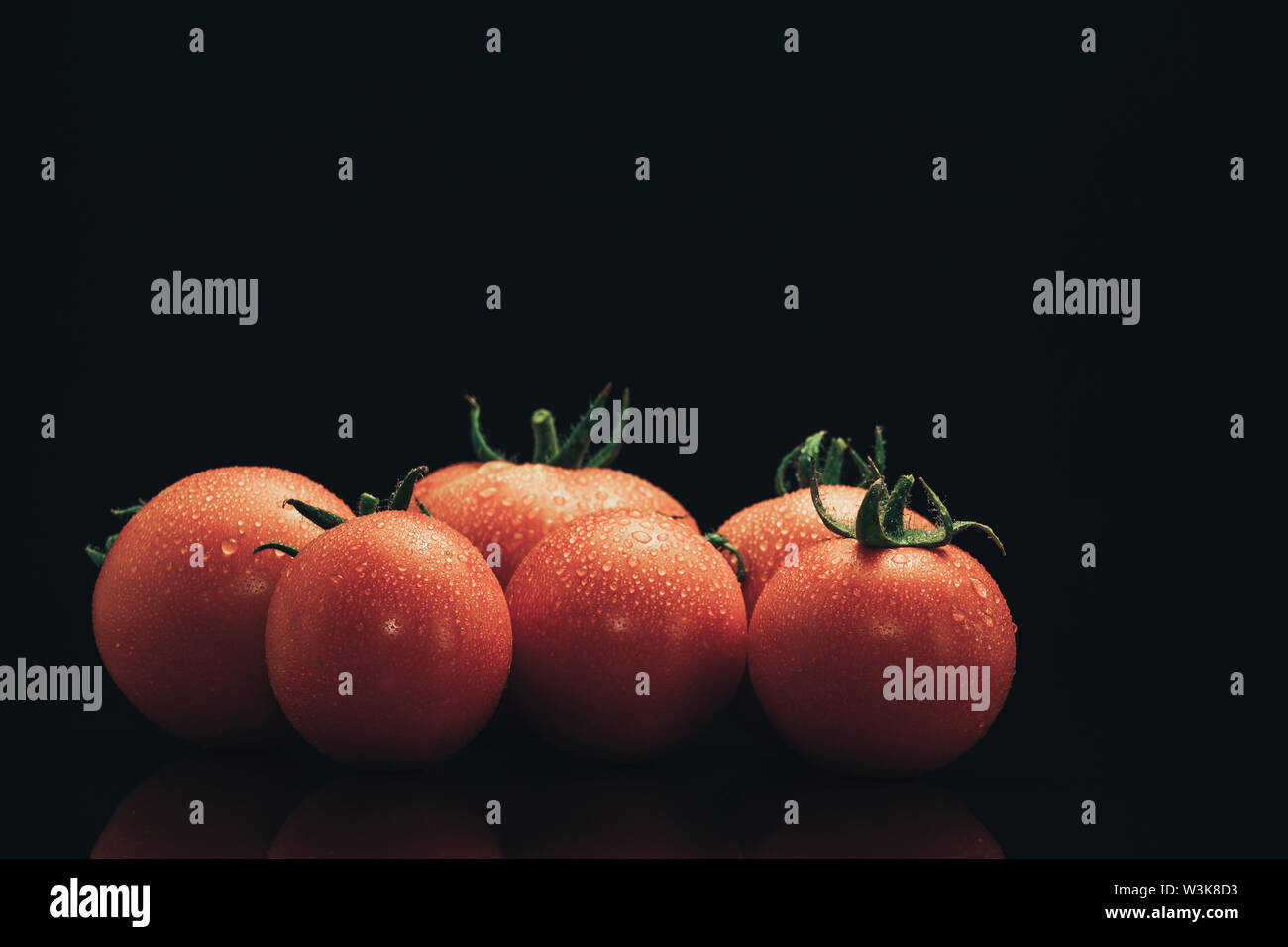 Fresh six tomato on a black glass table and dark background Stock Photo ...