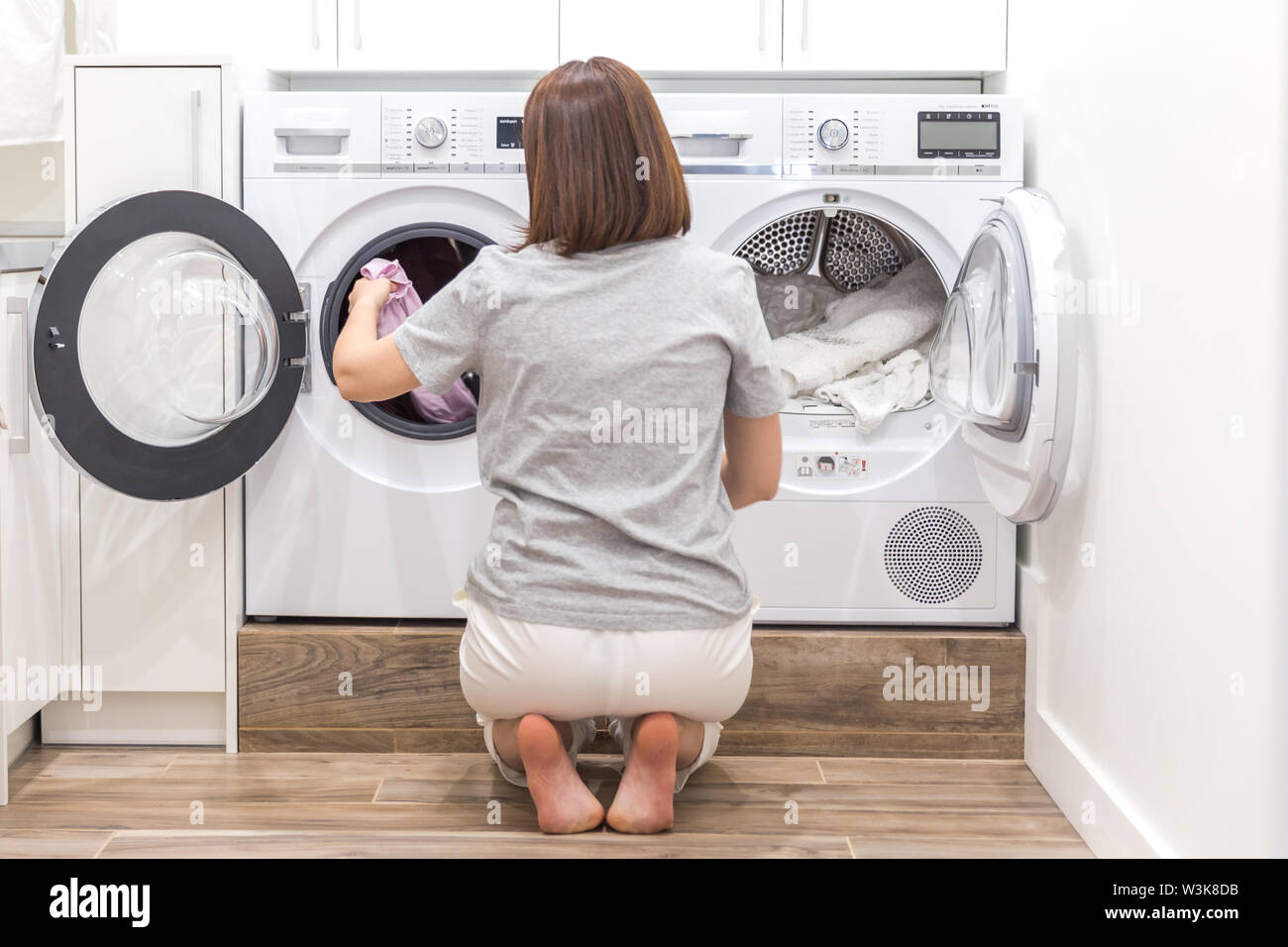 Woman Loading Dirty Clothes In Washing Machine For Washing In Utility ...