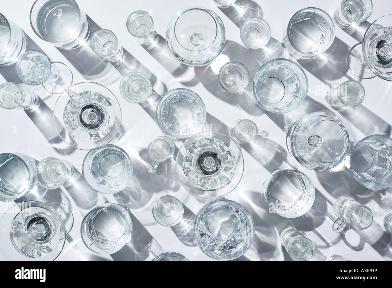 top view of transparent glasses with clear water on white background ...