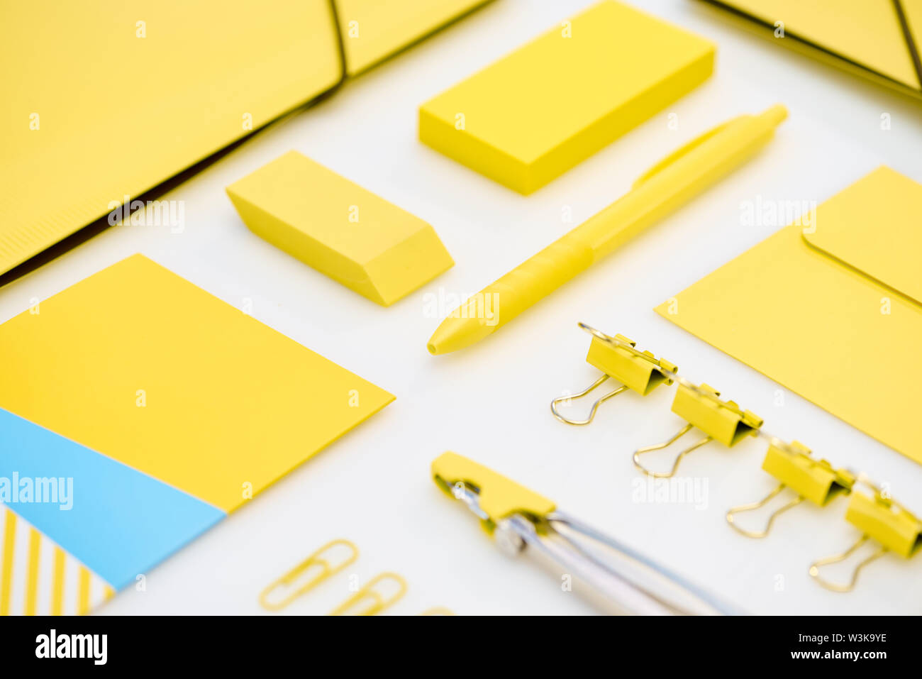 flat lay of yellow paper clips, compasses, envelope, pen, yellow and ...