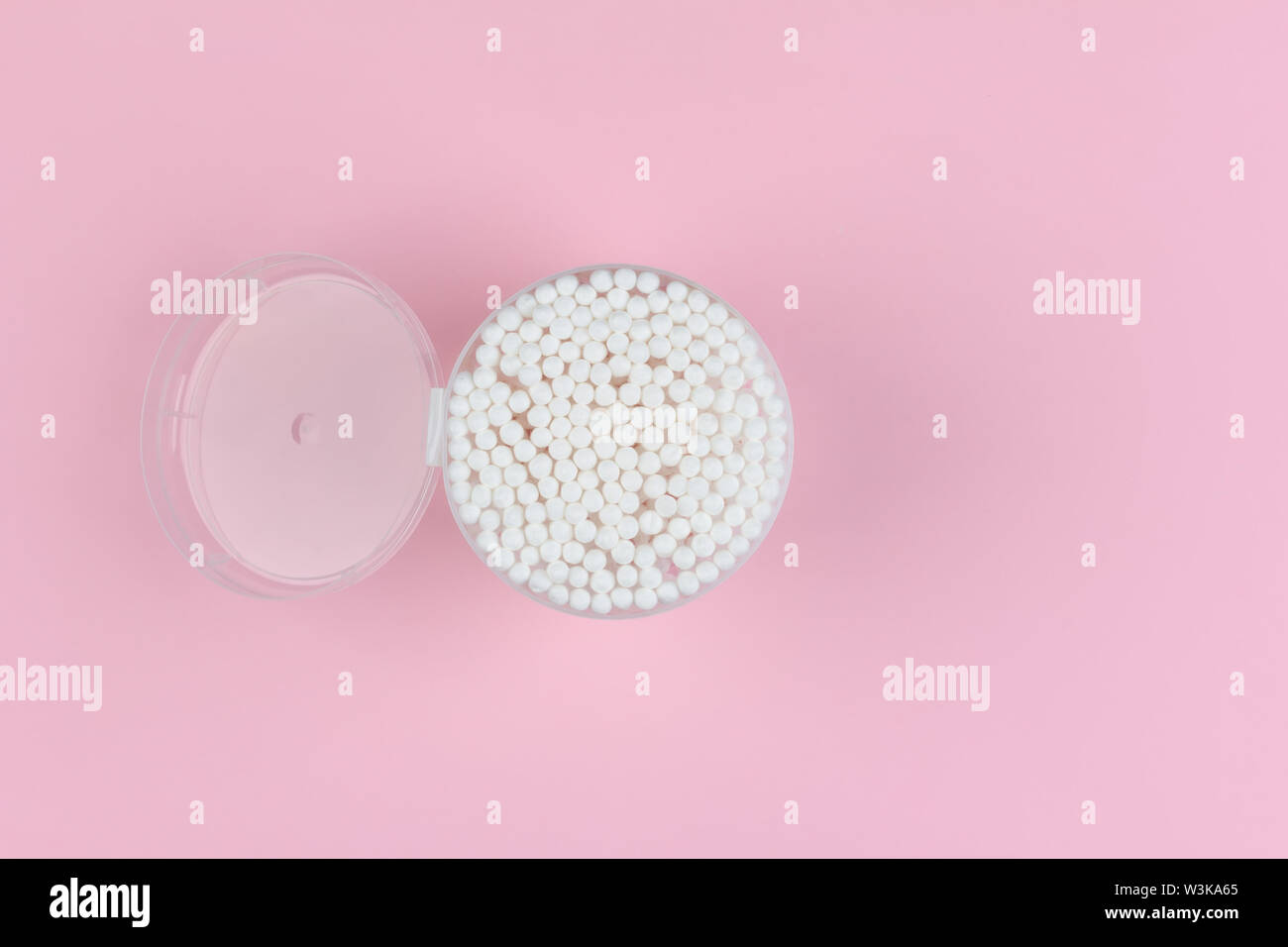 open plastic box with cotton swabs on light pink background top view ...