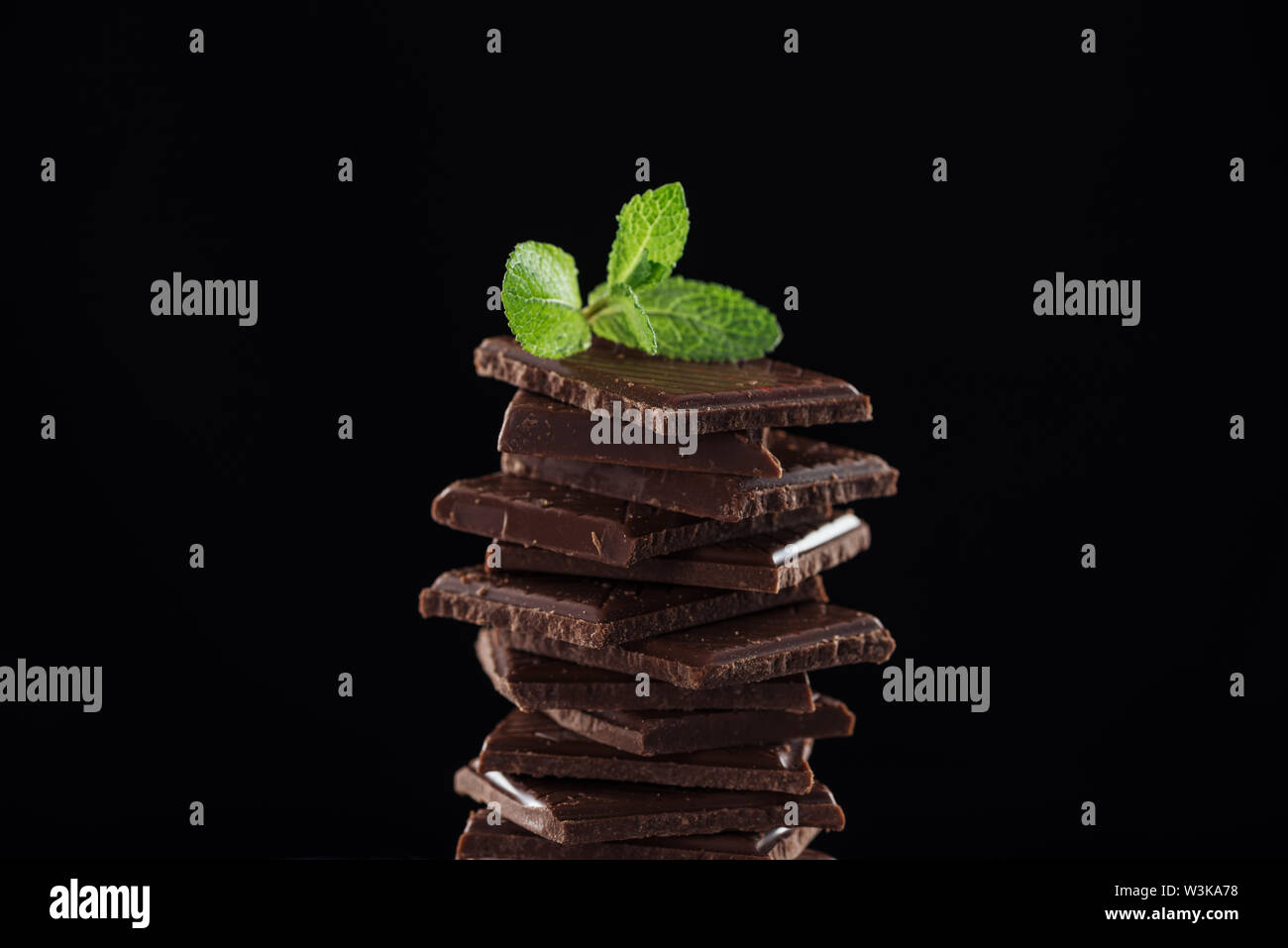 Dark chocolate stack with fresh mint, isolated on black Stock Photo - Alamy