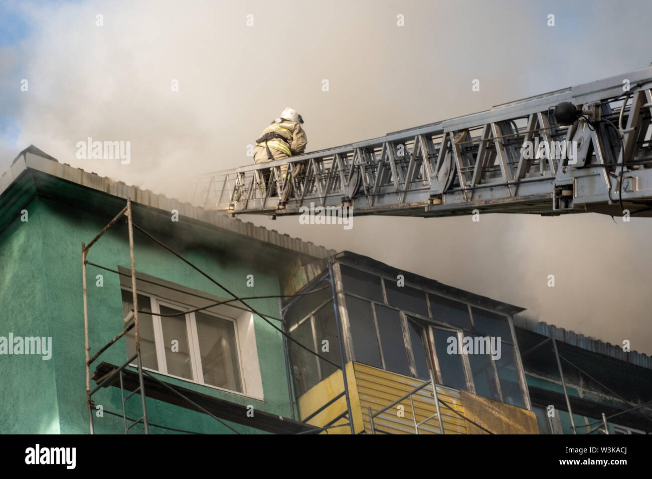 Firefighters on the stairs extinguish a fire on the roof of a ...
