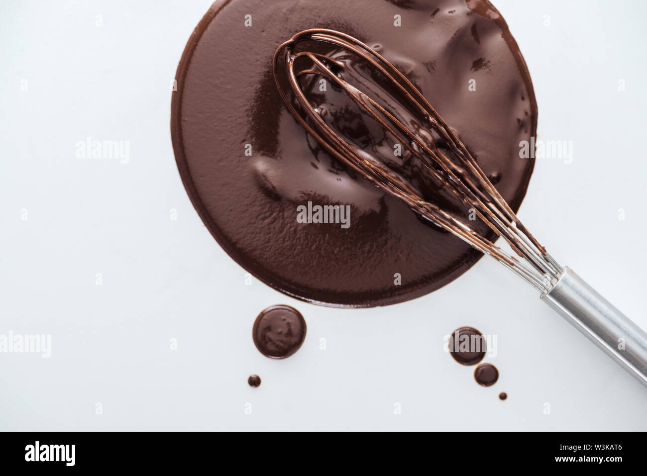 Top view of dirty balloon whisk with circle of liquid chocolate on ...