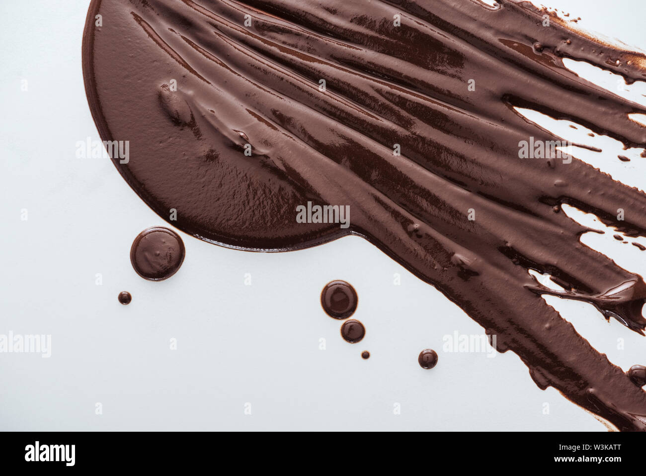 Top view of spilled dark chocolate and chocolate drops on white ...