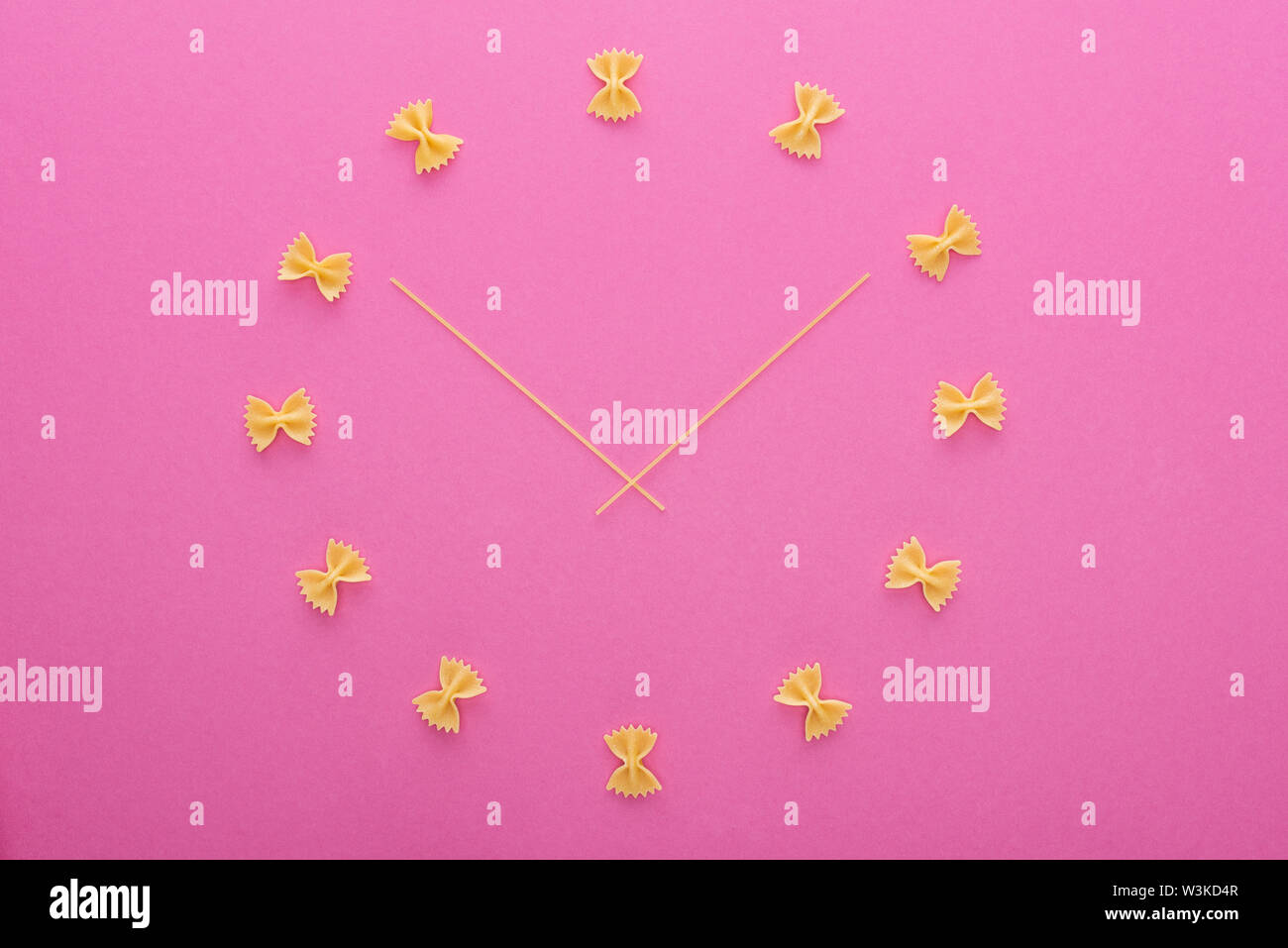 top view of clock concept with uncooked farfalle pasta and spaghetti in ...