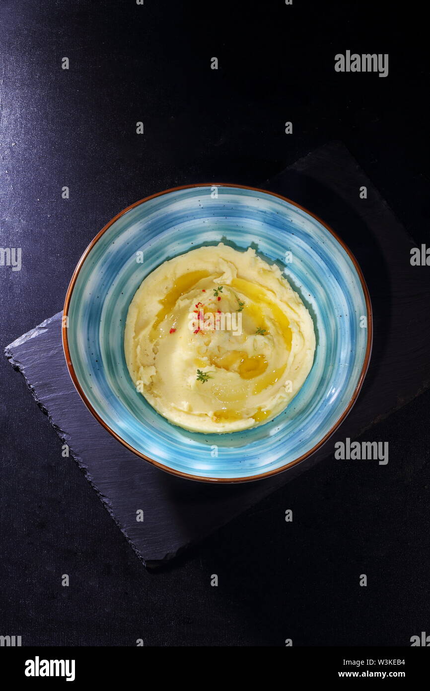 Puree in a blue plate on a black background Stock Photo - Alamy