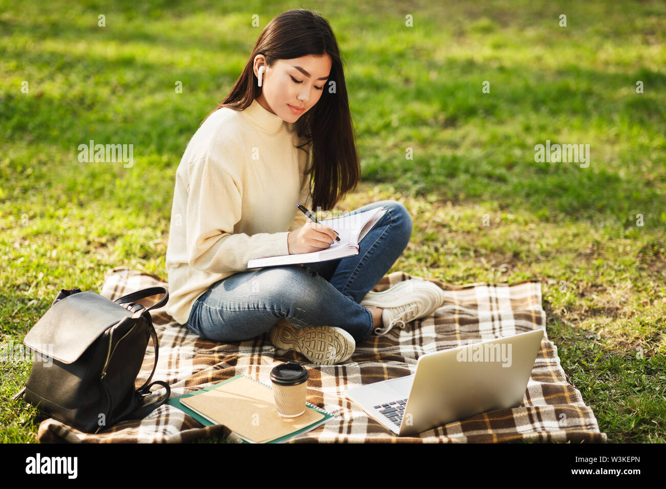 Asian girl doing homework, writing notes and using laptop Stock Photo ...