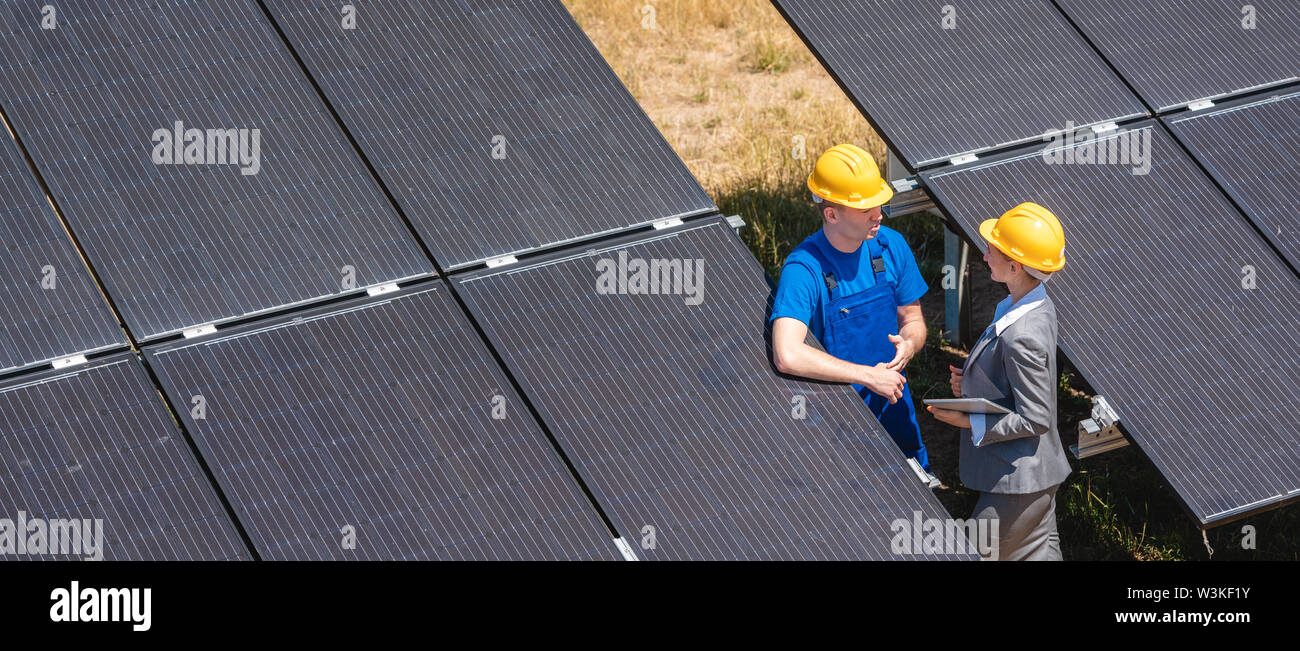 Two people standing amid solar cells in a power plant Stock Photo - Alamy