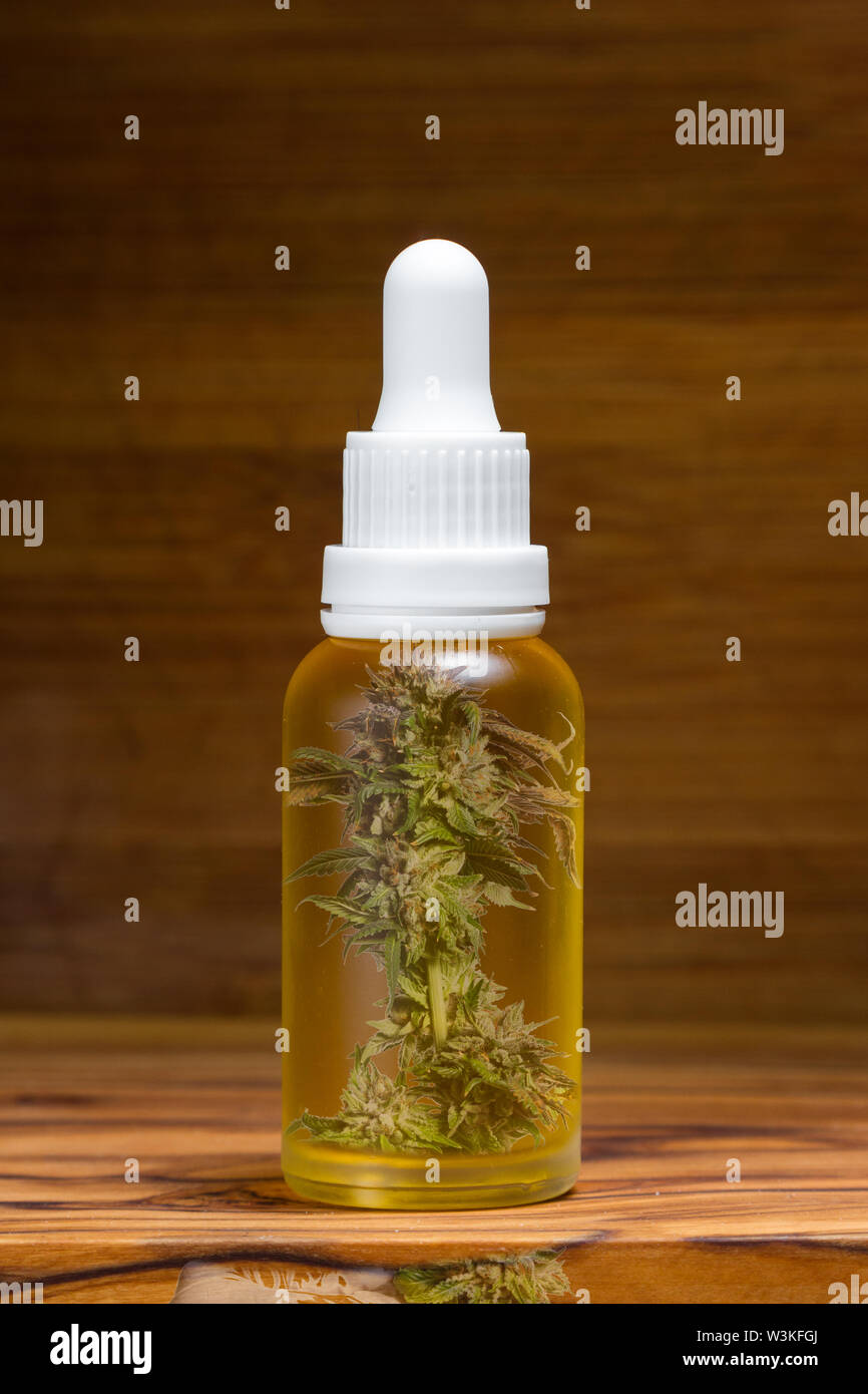 Pure hemp oil with vivid golden color in a dropper bottle on a wooden ...