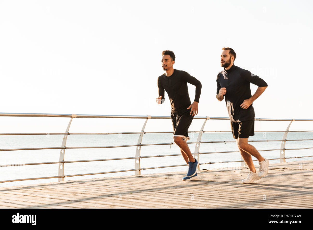Two attractive confident young healthy sportsmen jogging outdoors at ...