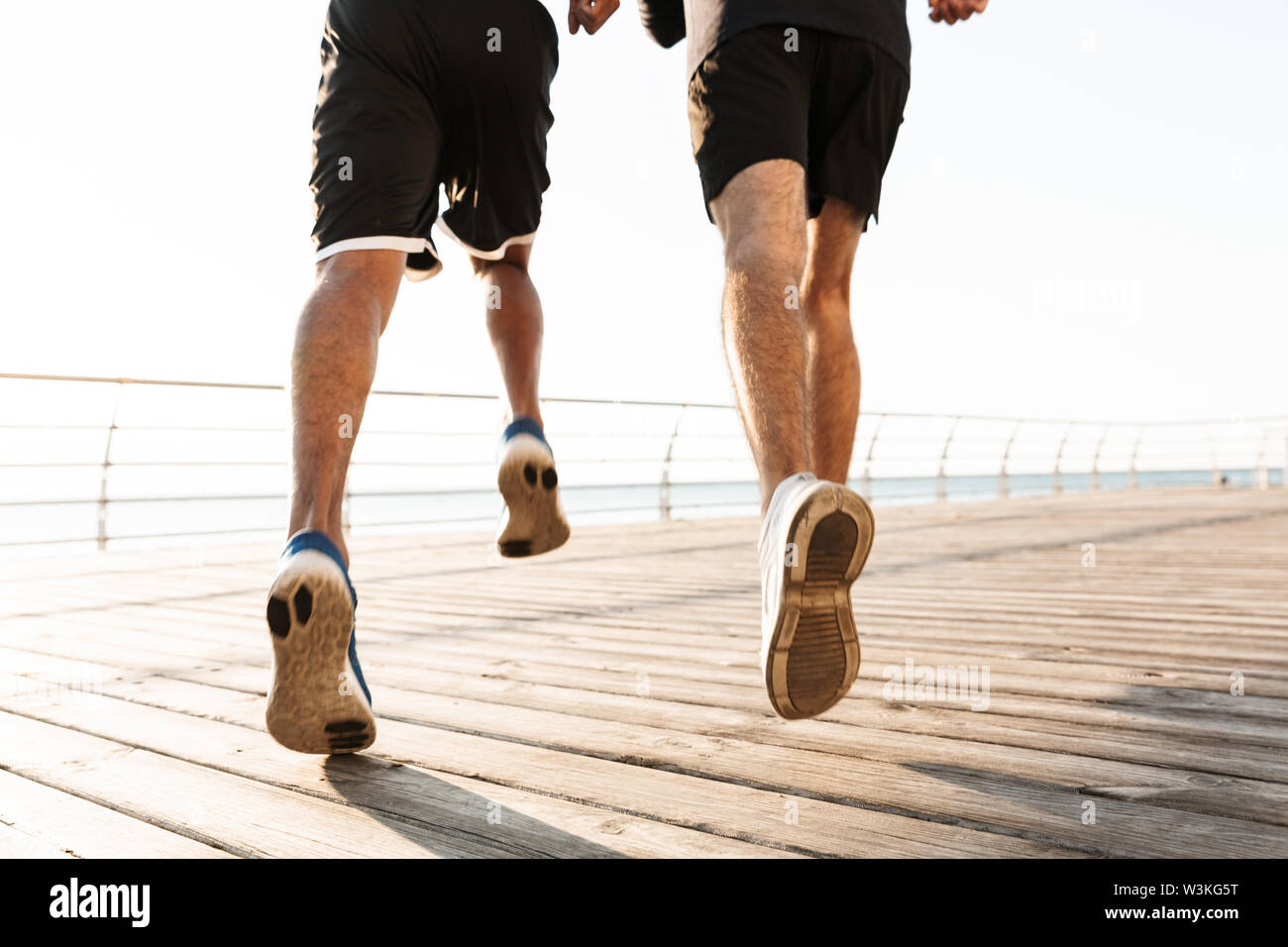Back view half portrait of two young healthy sportsmen jogging outdoors ...