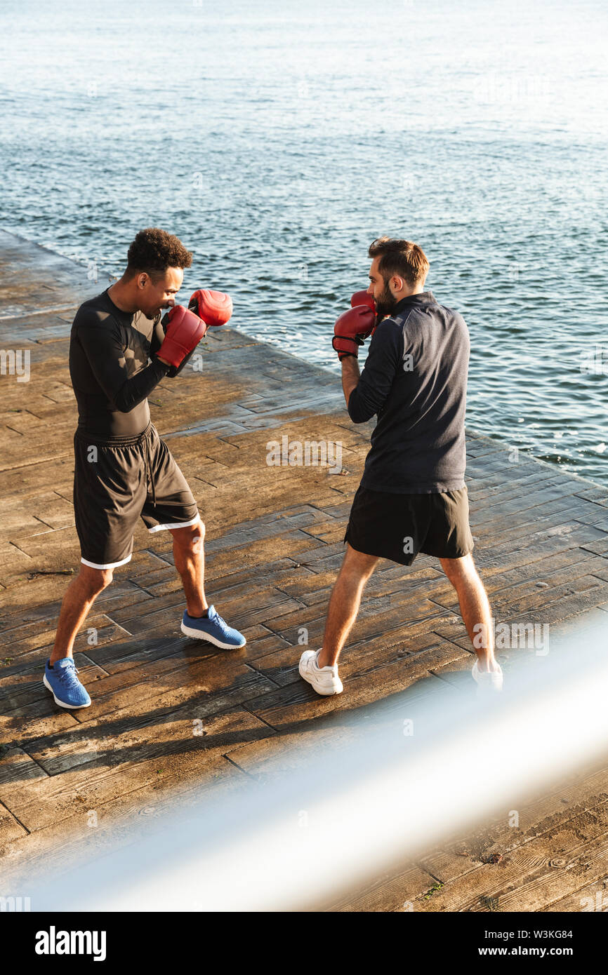 Two attractive confident young healthy sportsmen outdoors at the beach ...