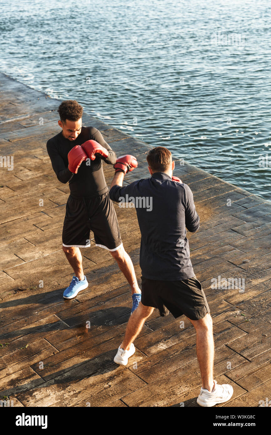 Two attractive confident young healthy sportsmen outdoors at the beach ...