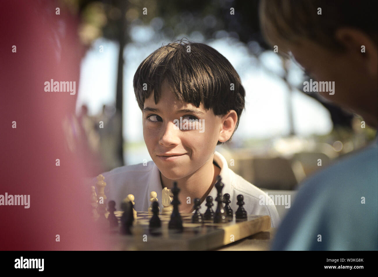 A young boy giving a side glance while at a game of chess Stock Photo ...
