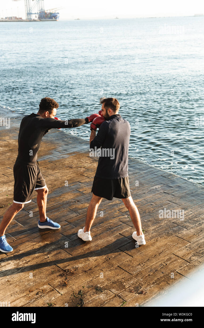 Two attractive confident young healthy sportsmen outdoors at the beach ...