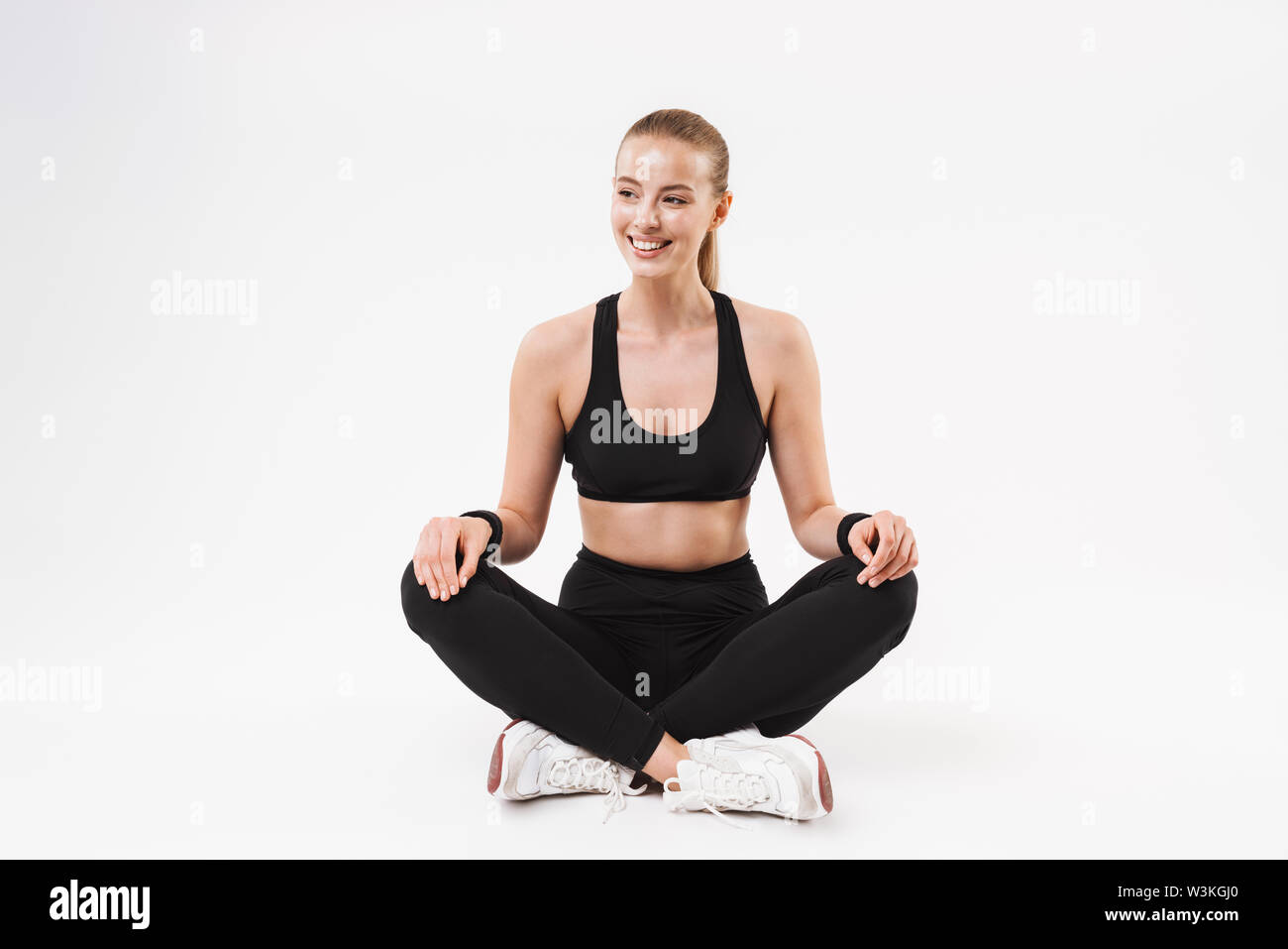 Image of pretty sporty woman wearing tracksuit sitting on floor with ...