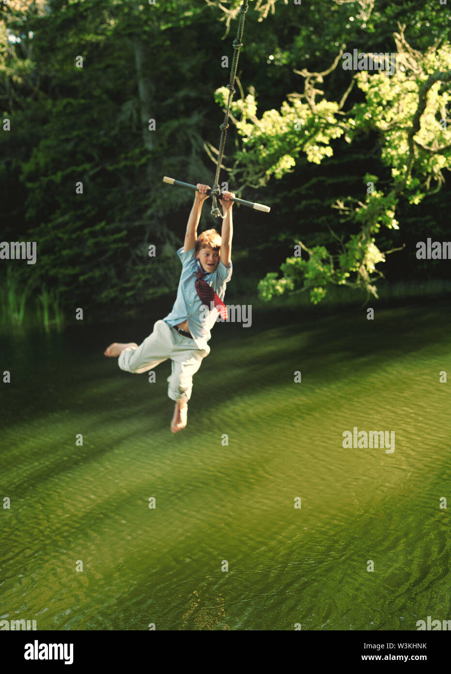 A boy swinging over a pond Stock Photo - Alamy