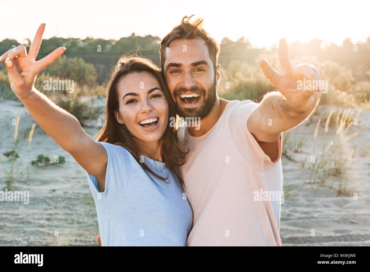 Beautiful young smiling couple spending time at the beach, showing ...