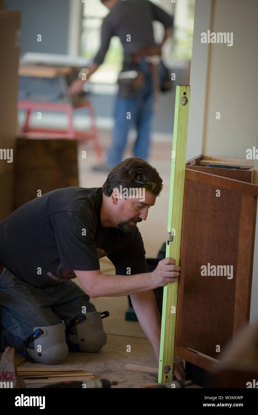 Male builder measuring a wooden cabinet Stock Photo - Alamy