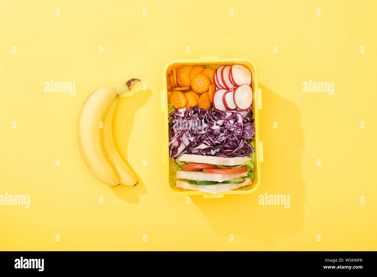 top view of lunch box with sandwiches and vegetables near bananas Stock ...
