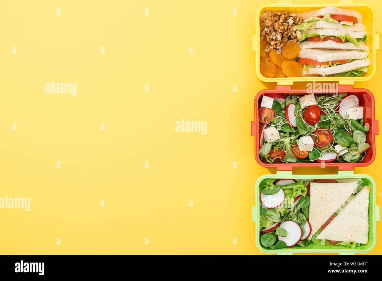 top view of three lunch boxes with food on yellow background Stock ...