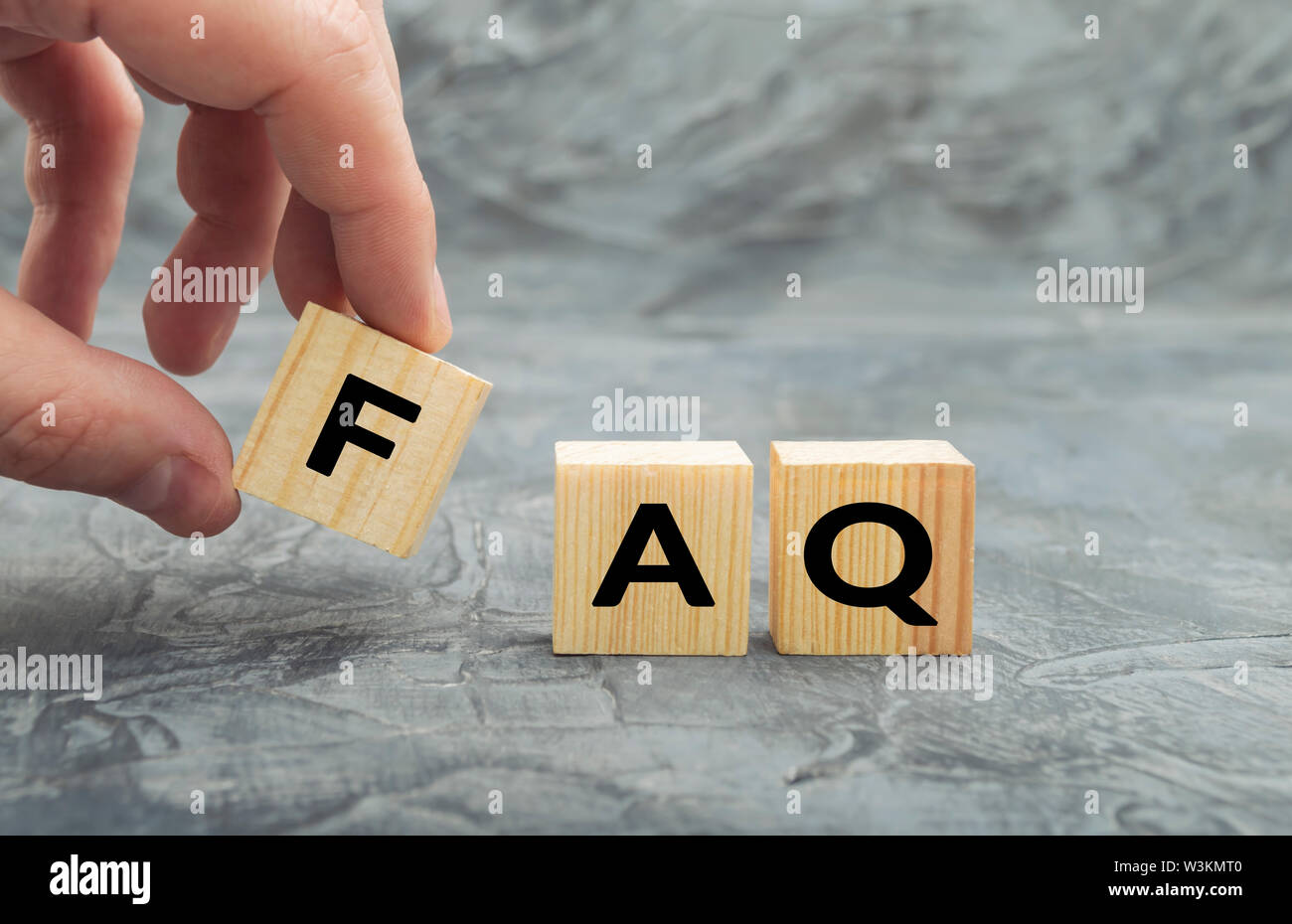 Hand putting wooden cube block with word FAQ (frequently asked ...