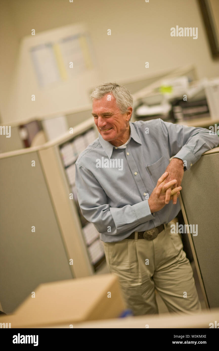 Smiling mature man leaning on the wall of an office cubicle Stock Photo ...