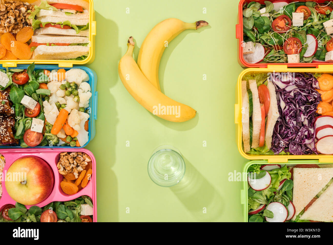 top view of lunch boxes with food near glass of water and bananas Stock ...