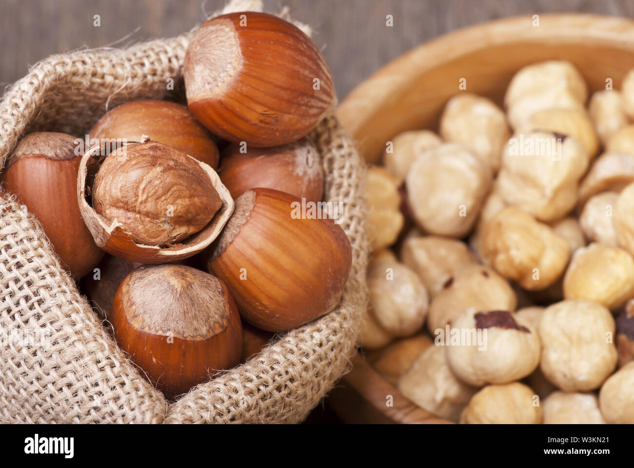 closeup of hazelnuts in shell in jute bag, on toasted peeled hazelnuts ...