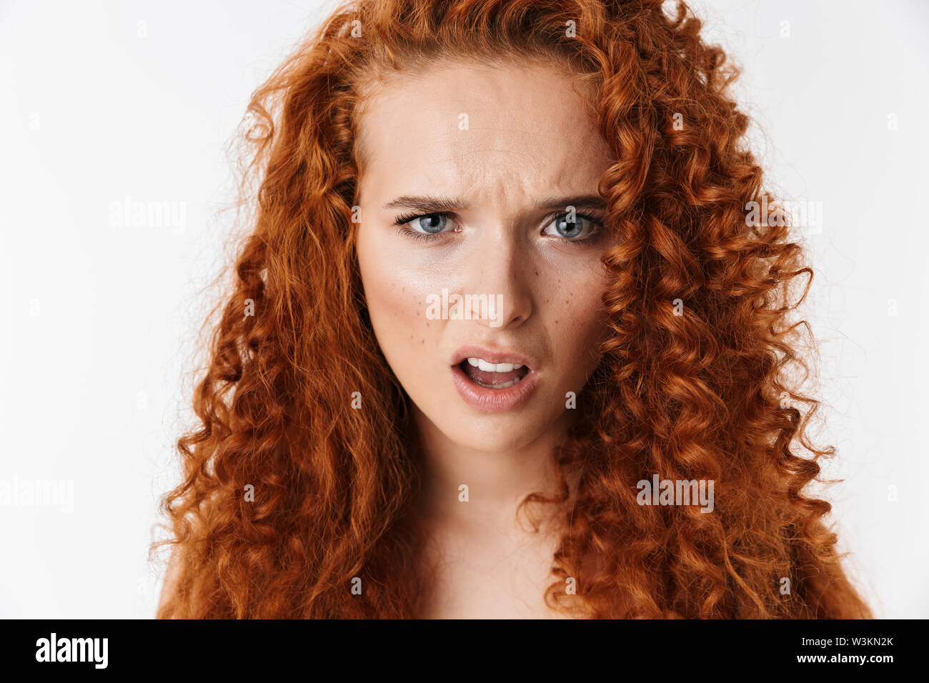 Close up portrait of an attractive confused young woman with long curly ...