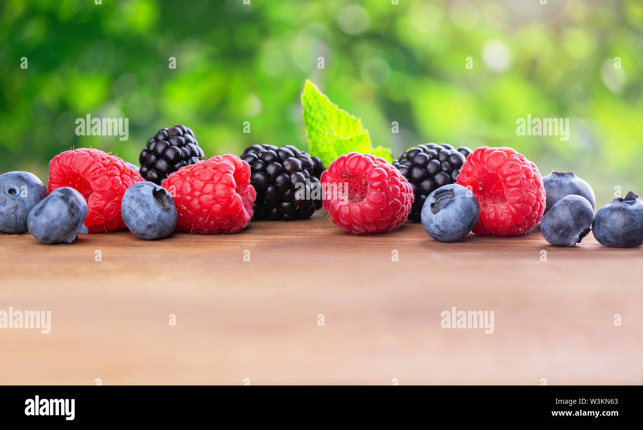 A bunch of wild berries on a wooden table and leaf background, template ...