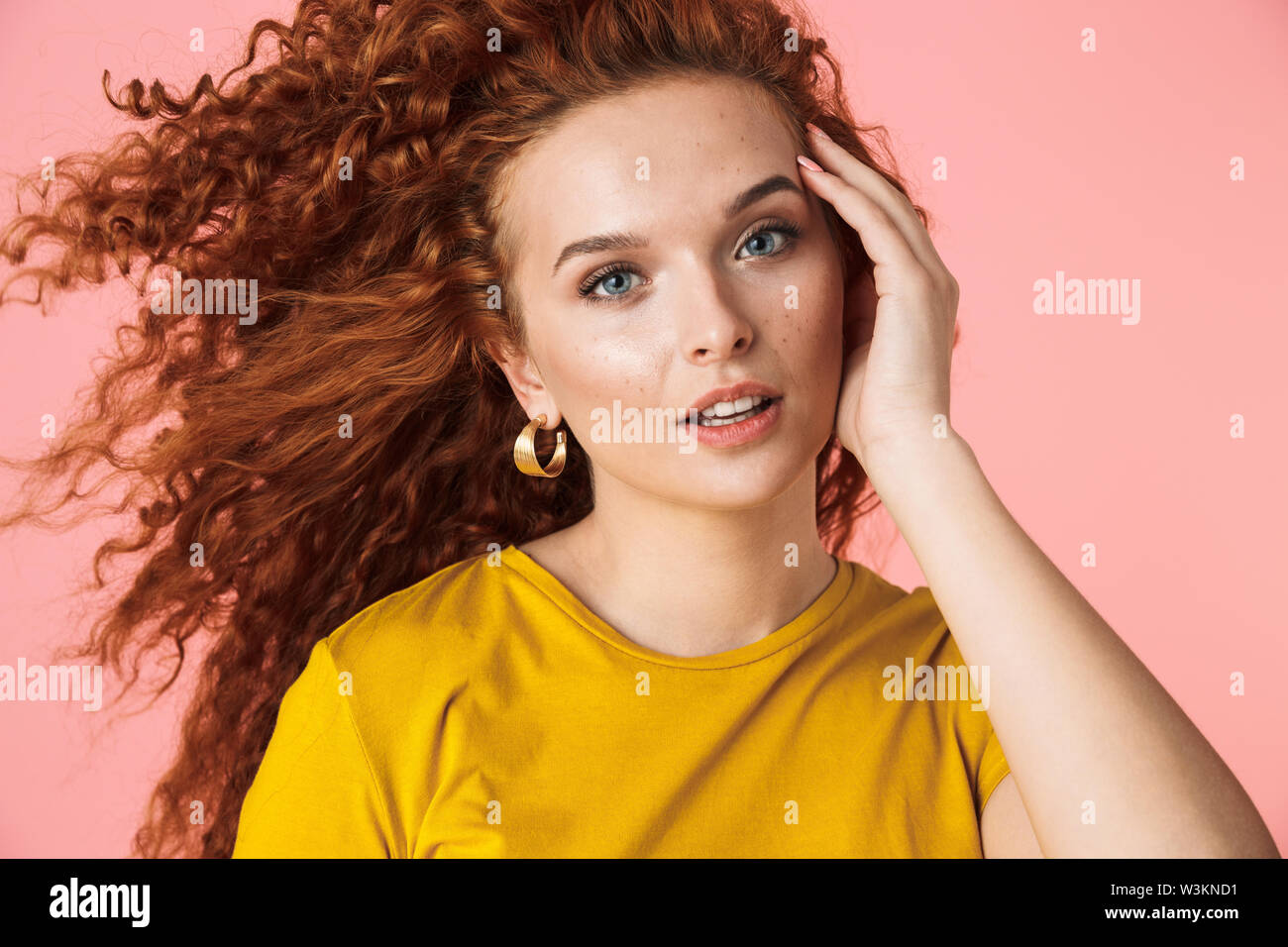 Close up portrait of an attractive young woman with long curly red hair ...