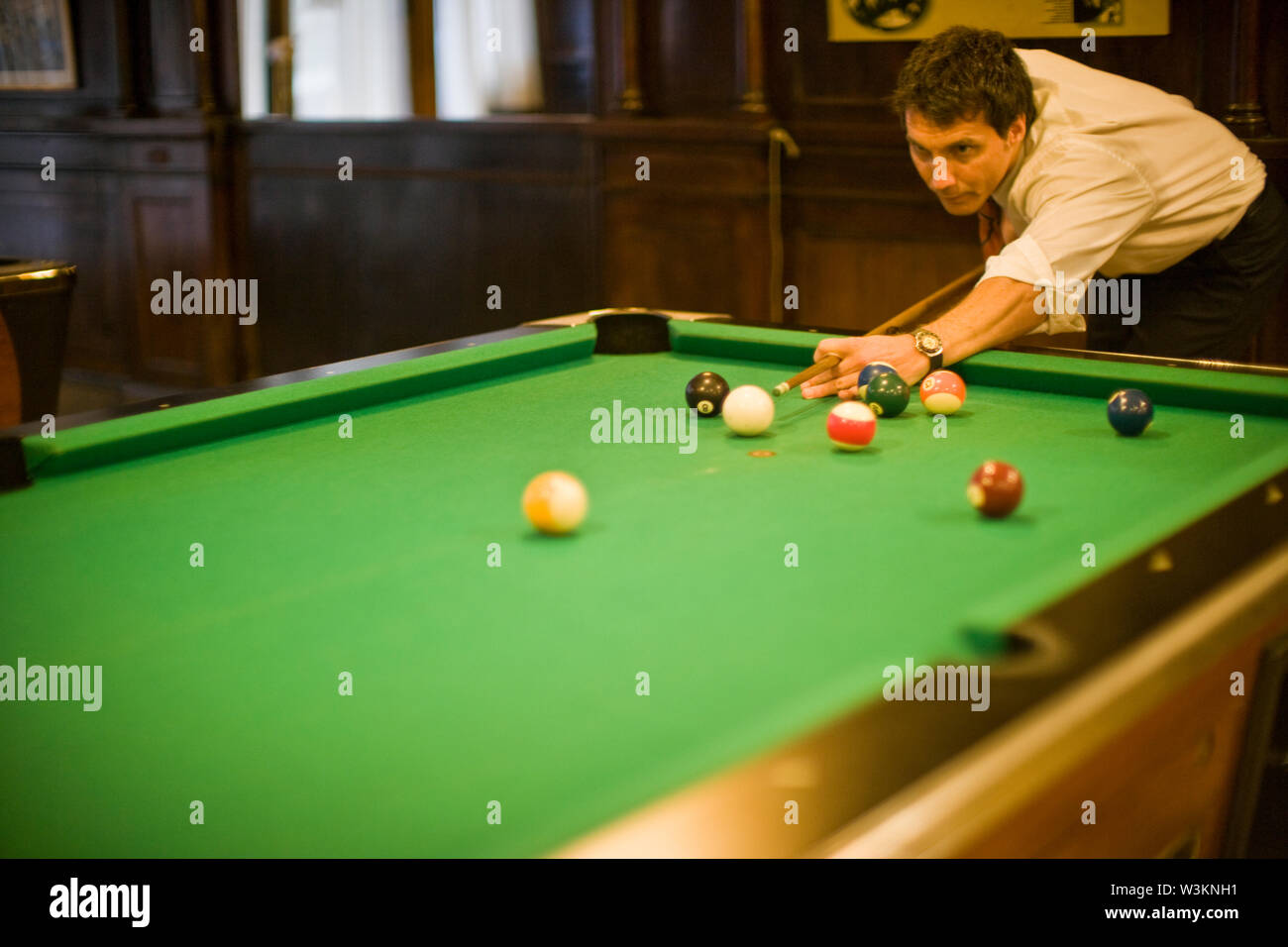 Young business man getting ready to shoot a ball with his cue during a ...