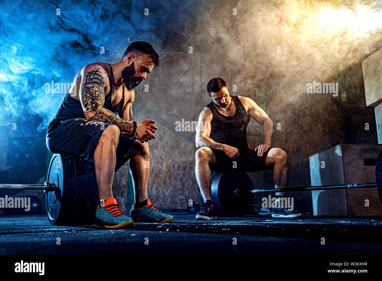 Two muscular bearded tattoed athletes relax after training, lifting ...