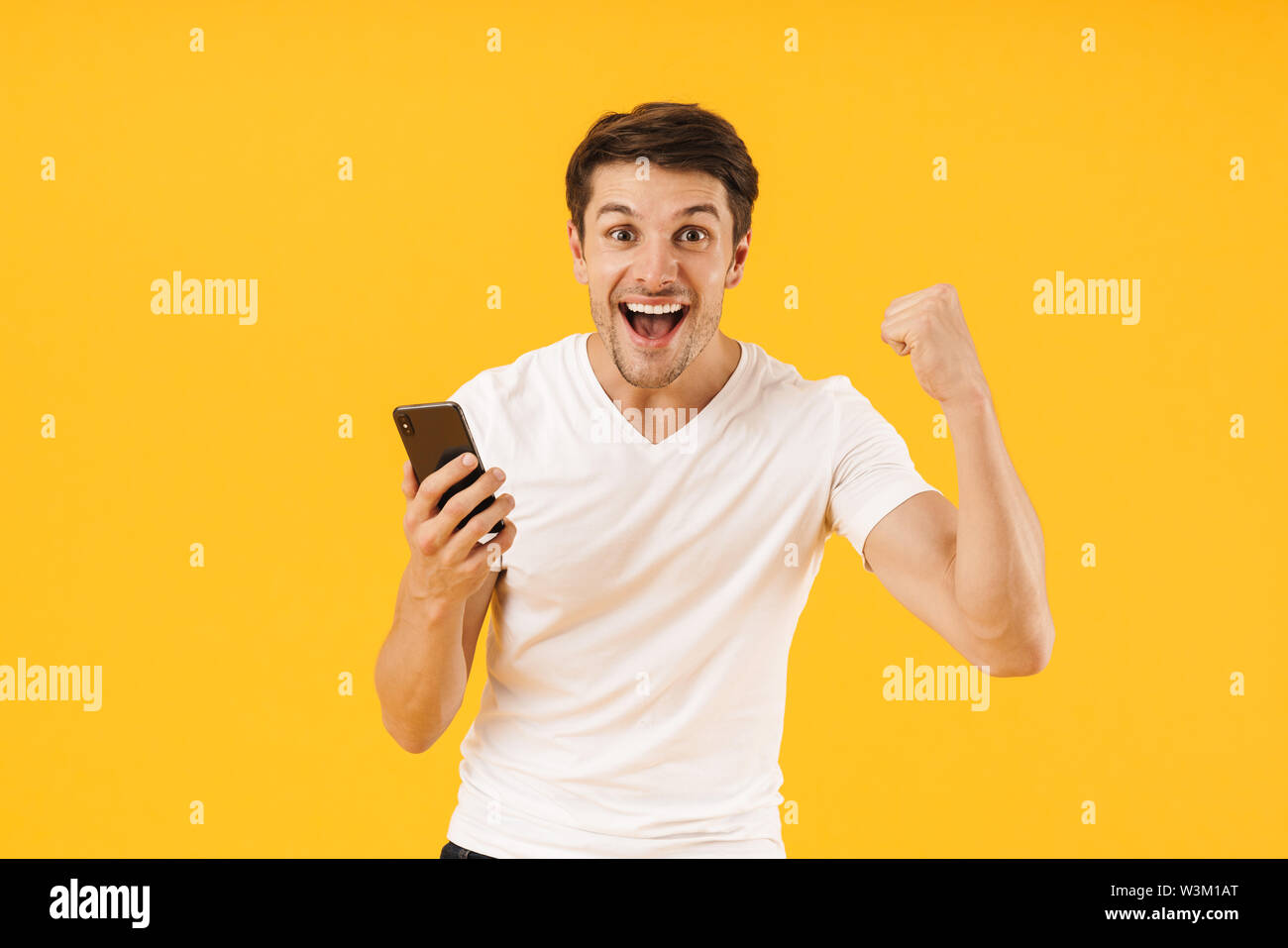 Image of a screaming happy shocked young man in casual white t-shirt ...