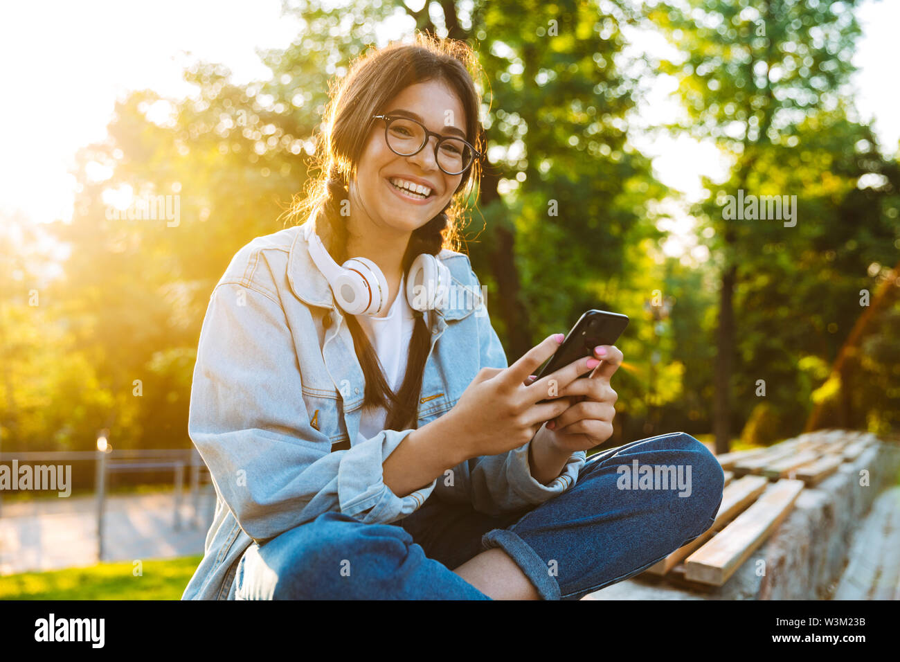 Picture of a happy cute young student girl wearing eyeglasses sitting ...