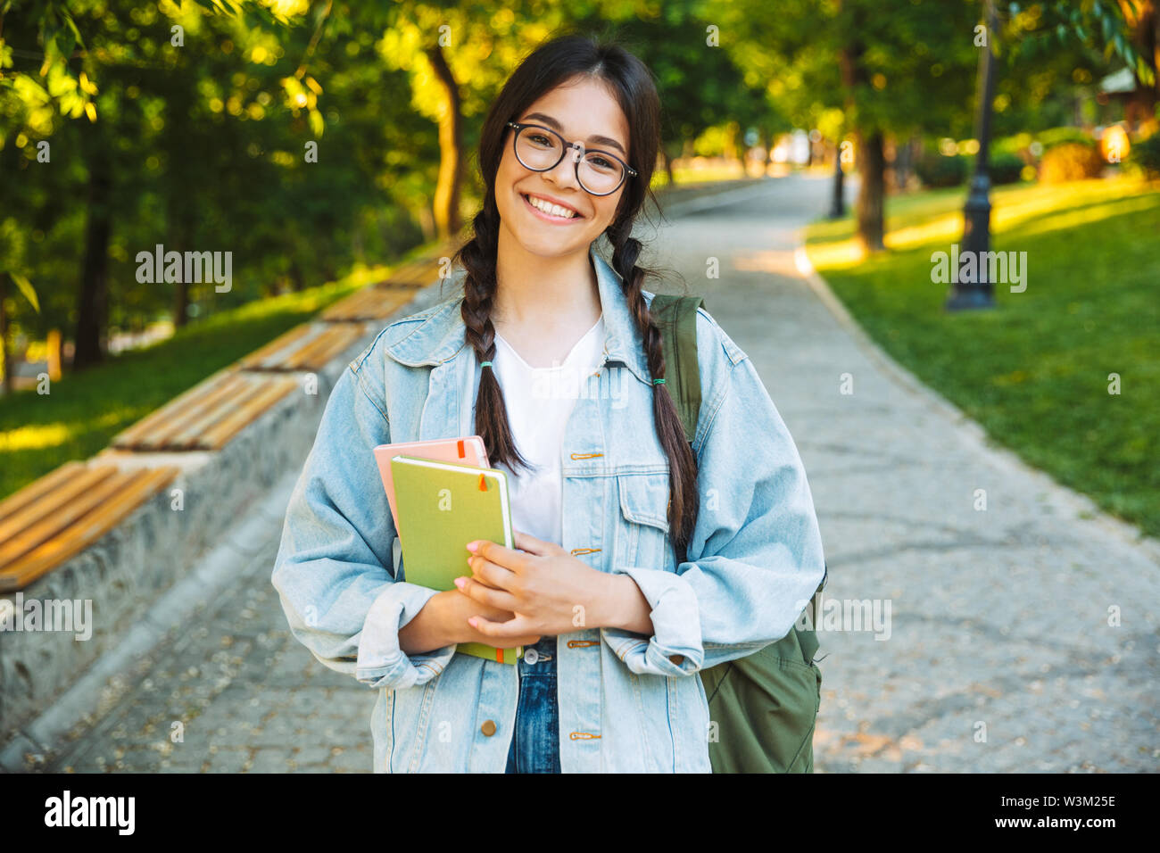 Happy young teenage student girl carrying backpack and books while ...