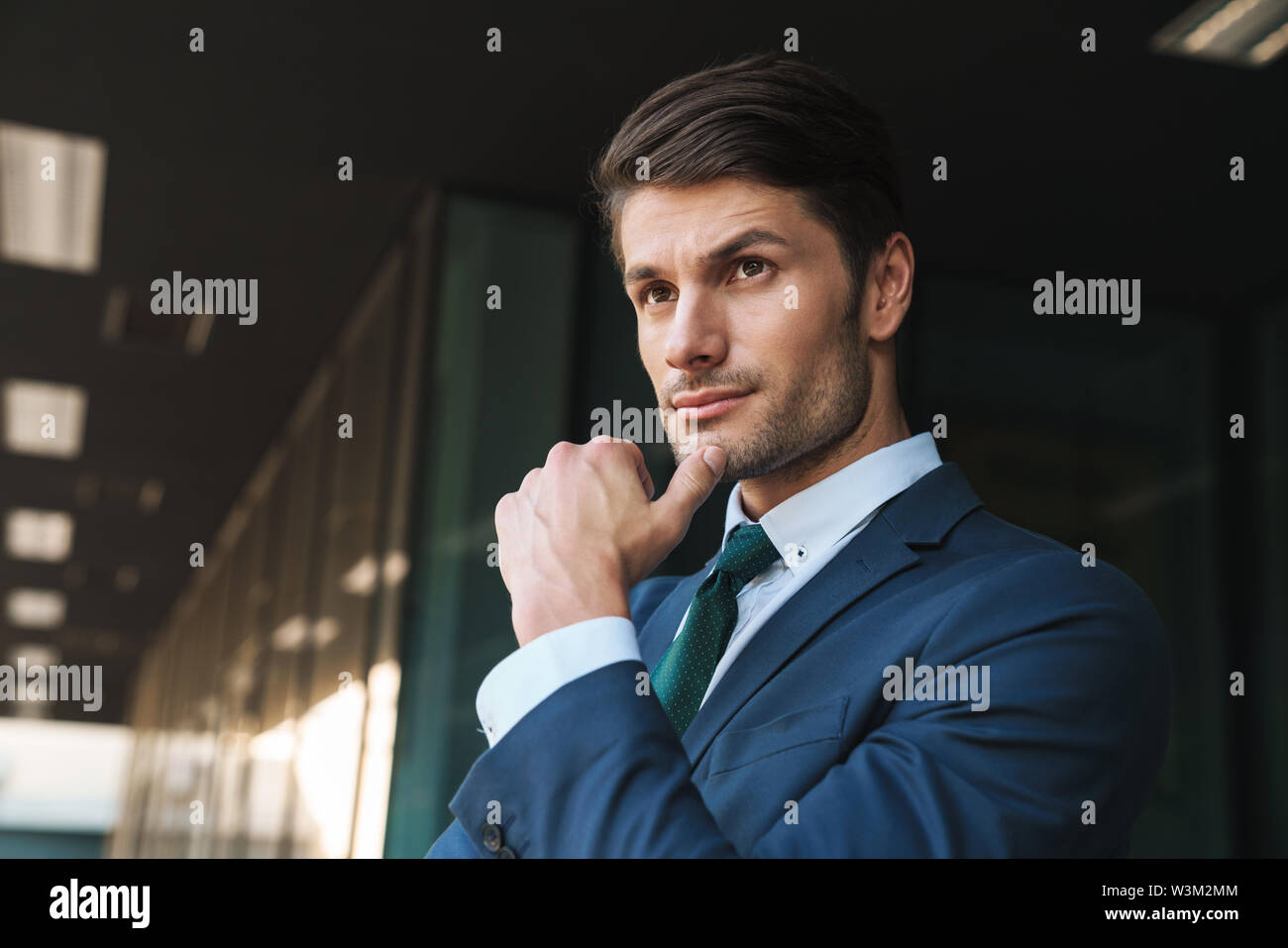 Photo of handsome businessman dressed in formal suit touching his chin ...