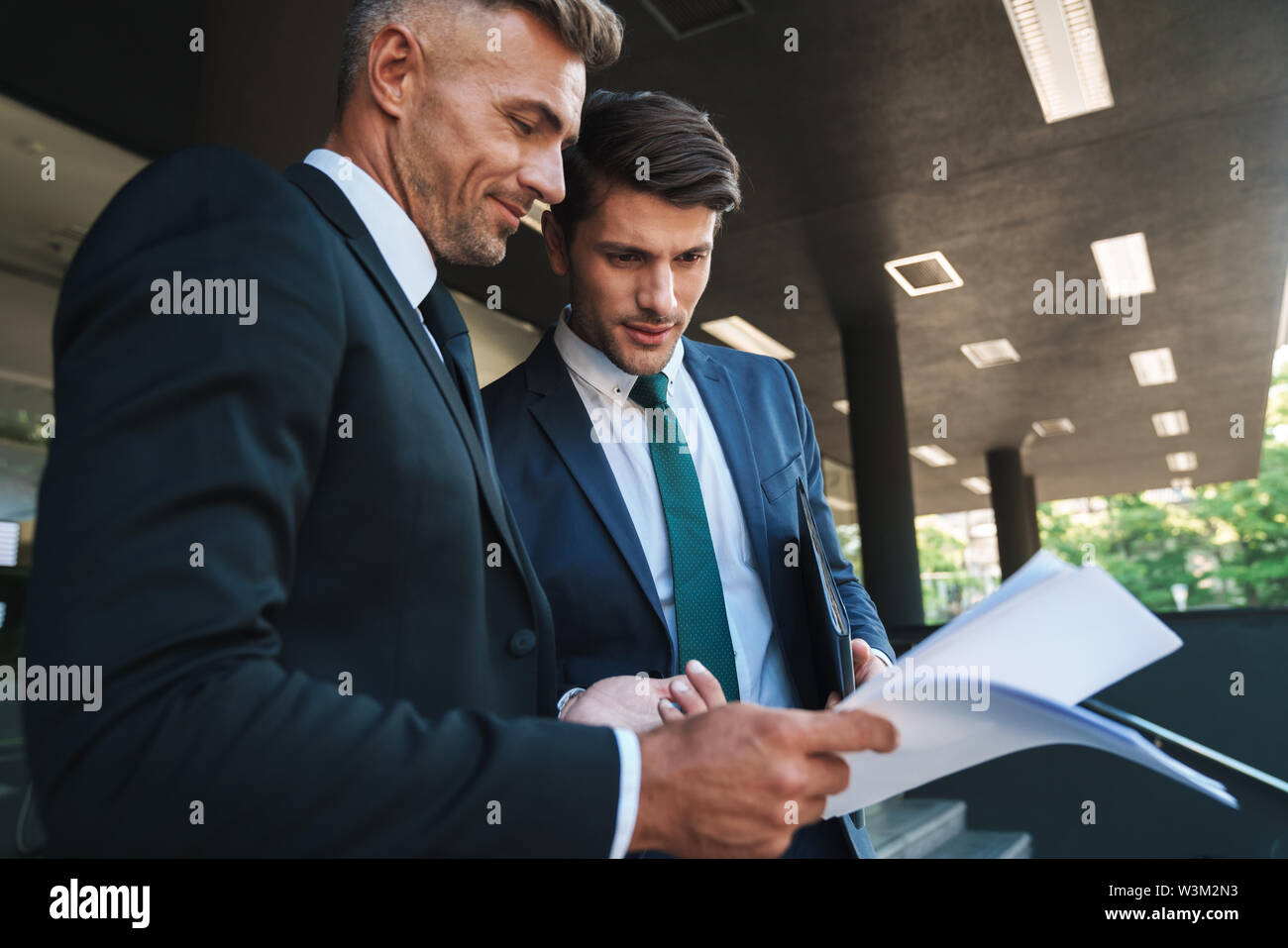 Image of young businessmen partners dressed in formal suit standing ...