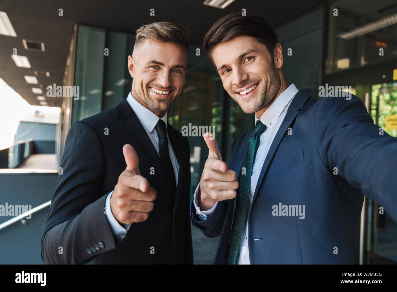 Photo of beautiful two businessmen dressed in formal suit showing ...